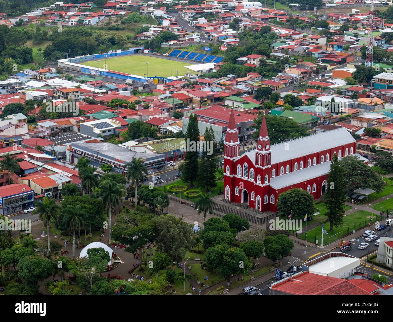 An aerial view of Grecia, Costa Rica with greenery and the red church ...