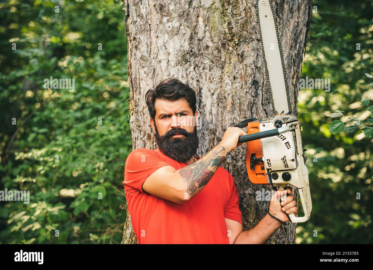 Lumberjack worker standing in the forest with chainsaw. Deforestation ...