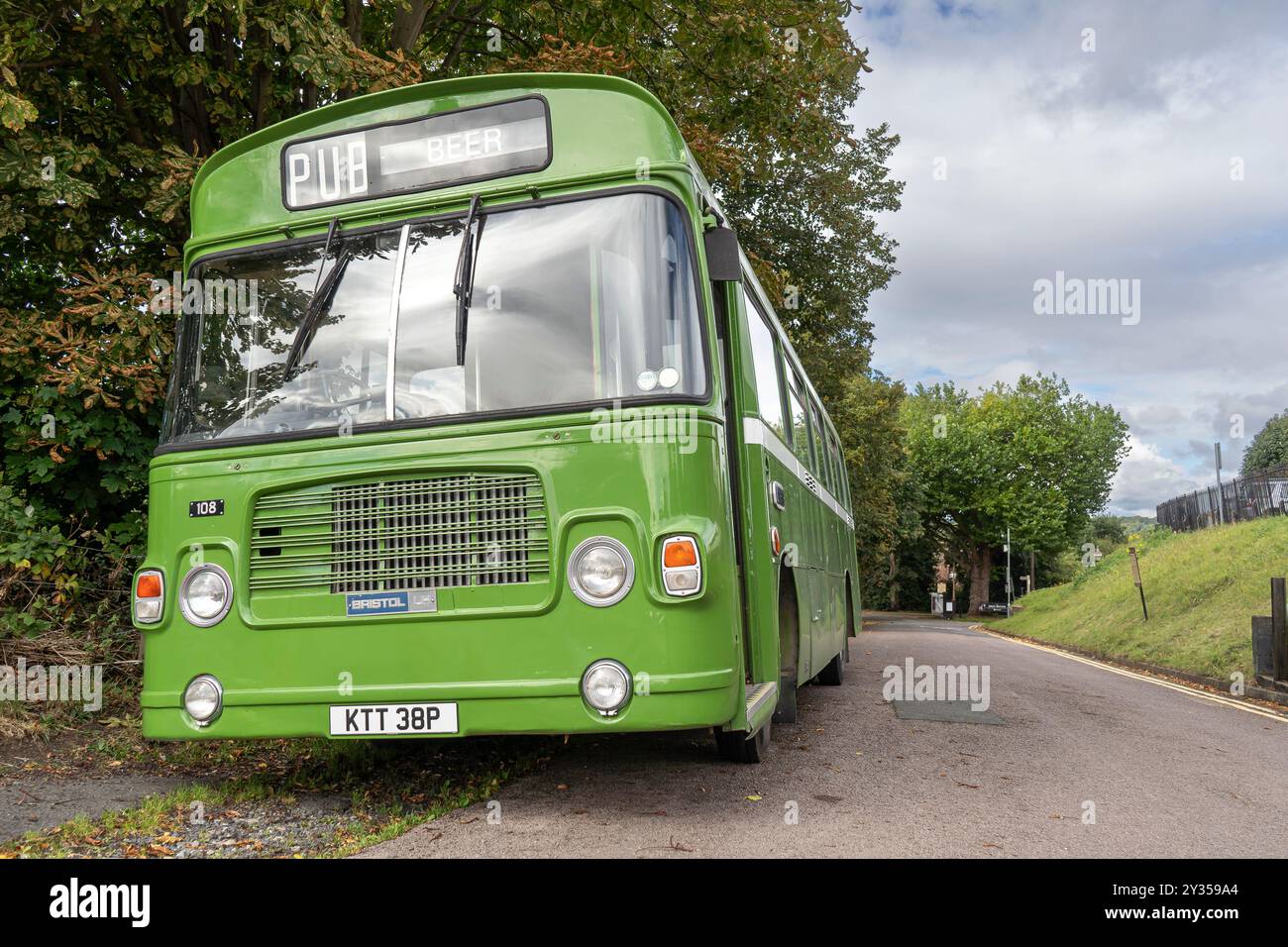 Vintage green Bristol bus parked on a UK side road under a tree ...