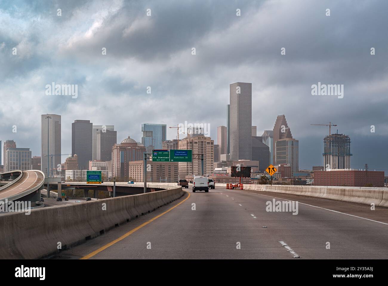 A wide highway leading into downtown Houston with towering skyscrapers ...