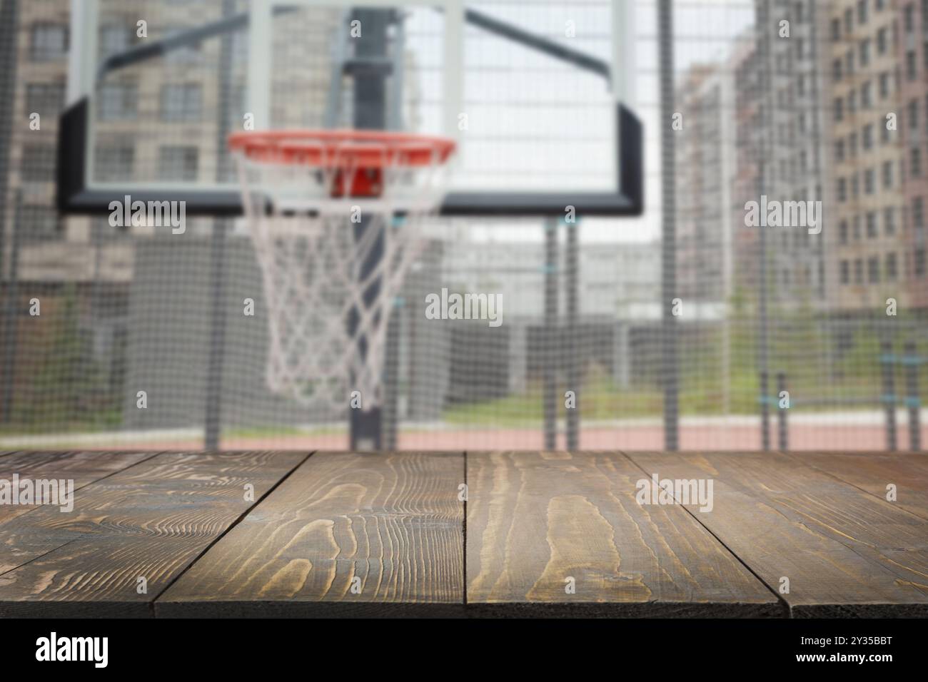 Empty wooden table top with blurred outdoor basketball hoop on sports ...