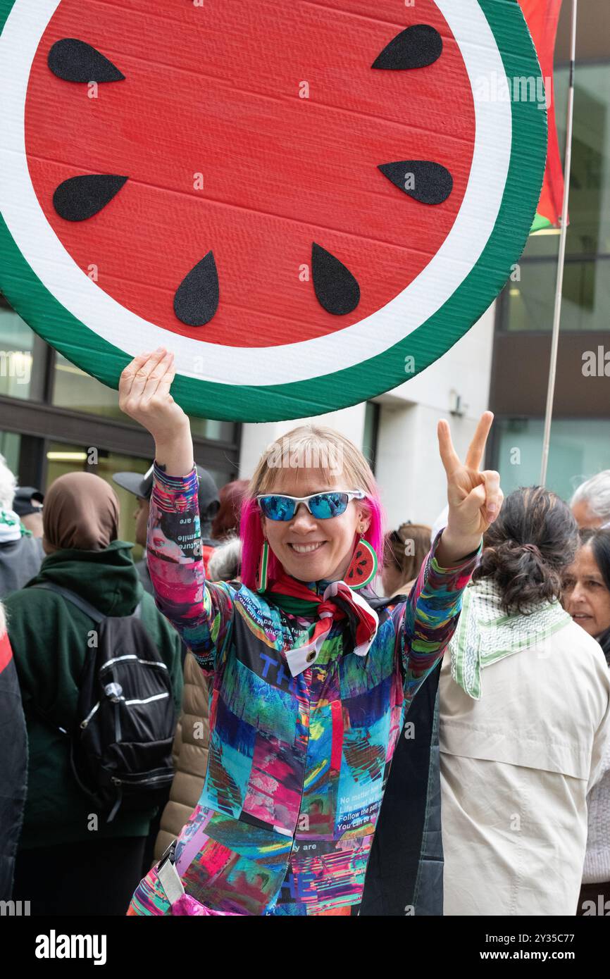 London, UK. 12 September, 2024. A woman holds a placard depicting a ...
