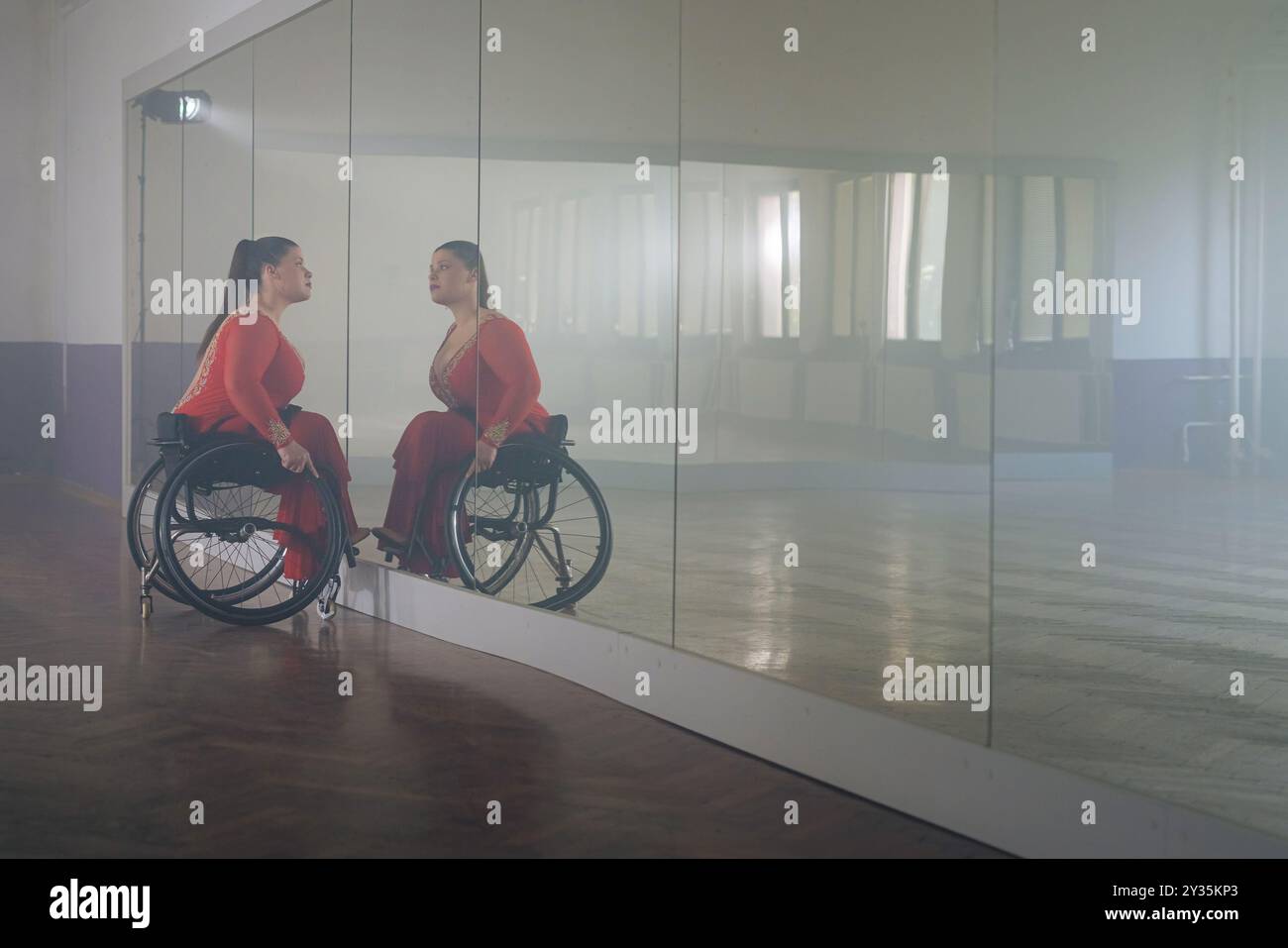 Beautiful long-haired woman with a disability in a ballroom red dress ...