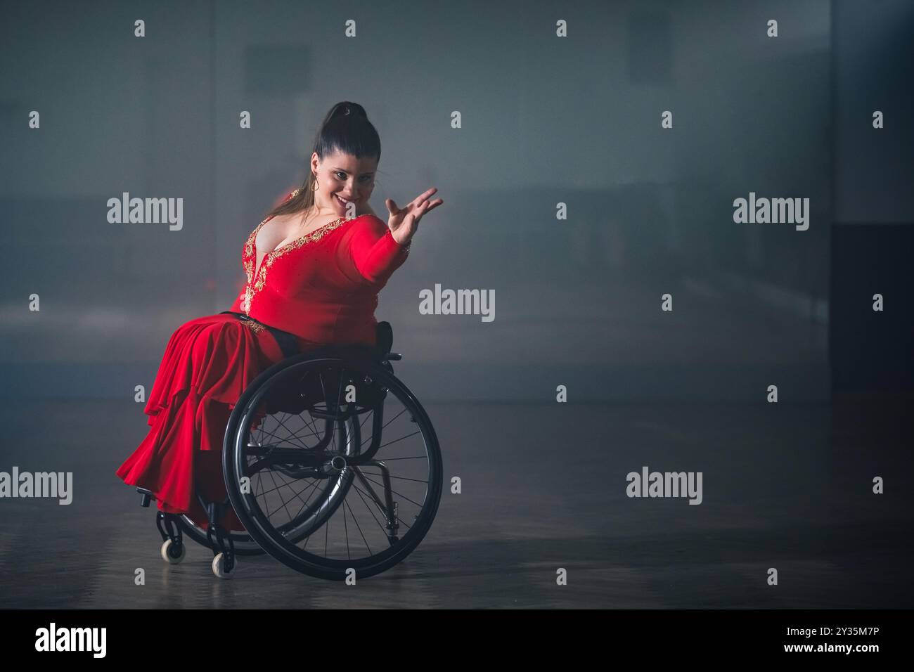 Woman in an elegant red dress dancing in a wheelchair, making graceful ...
