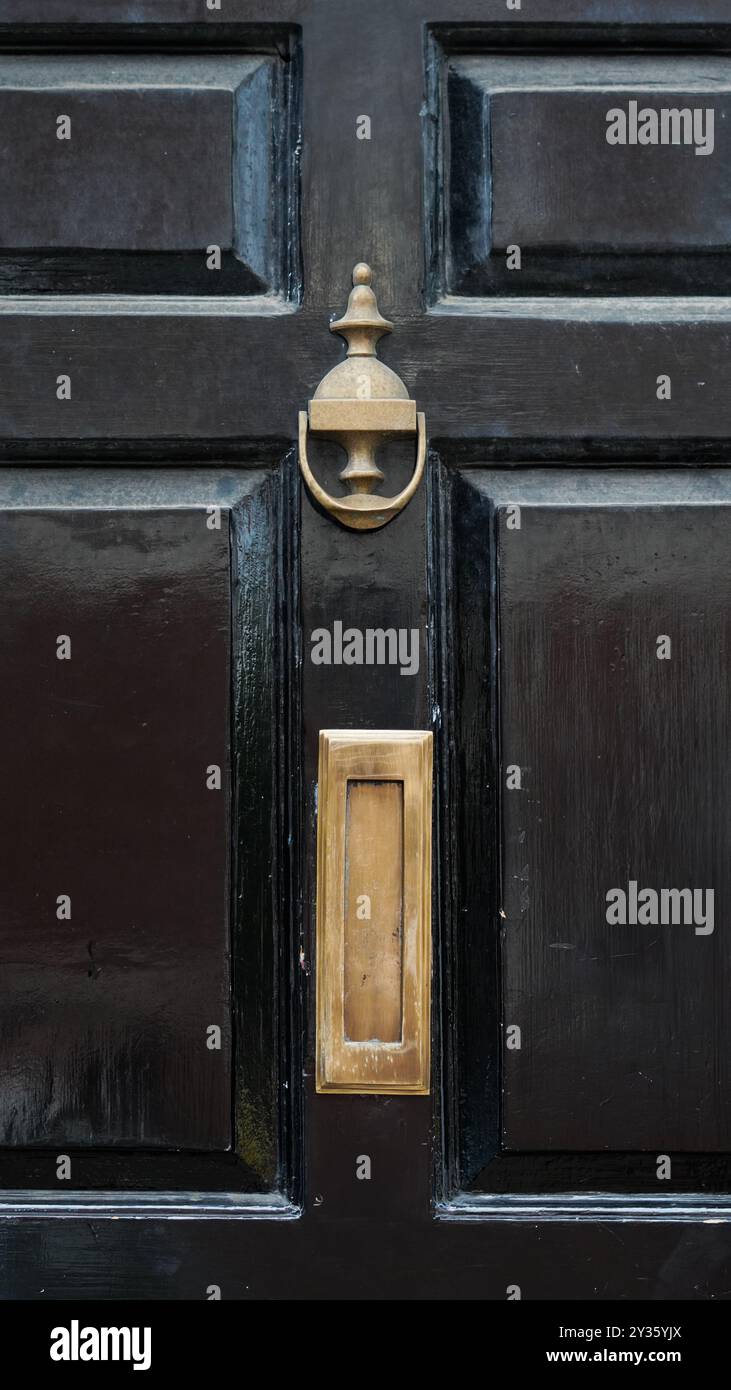 Close up of a dark blue British door with a golden knocker and ...