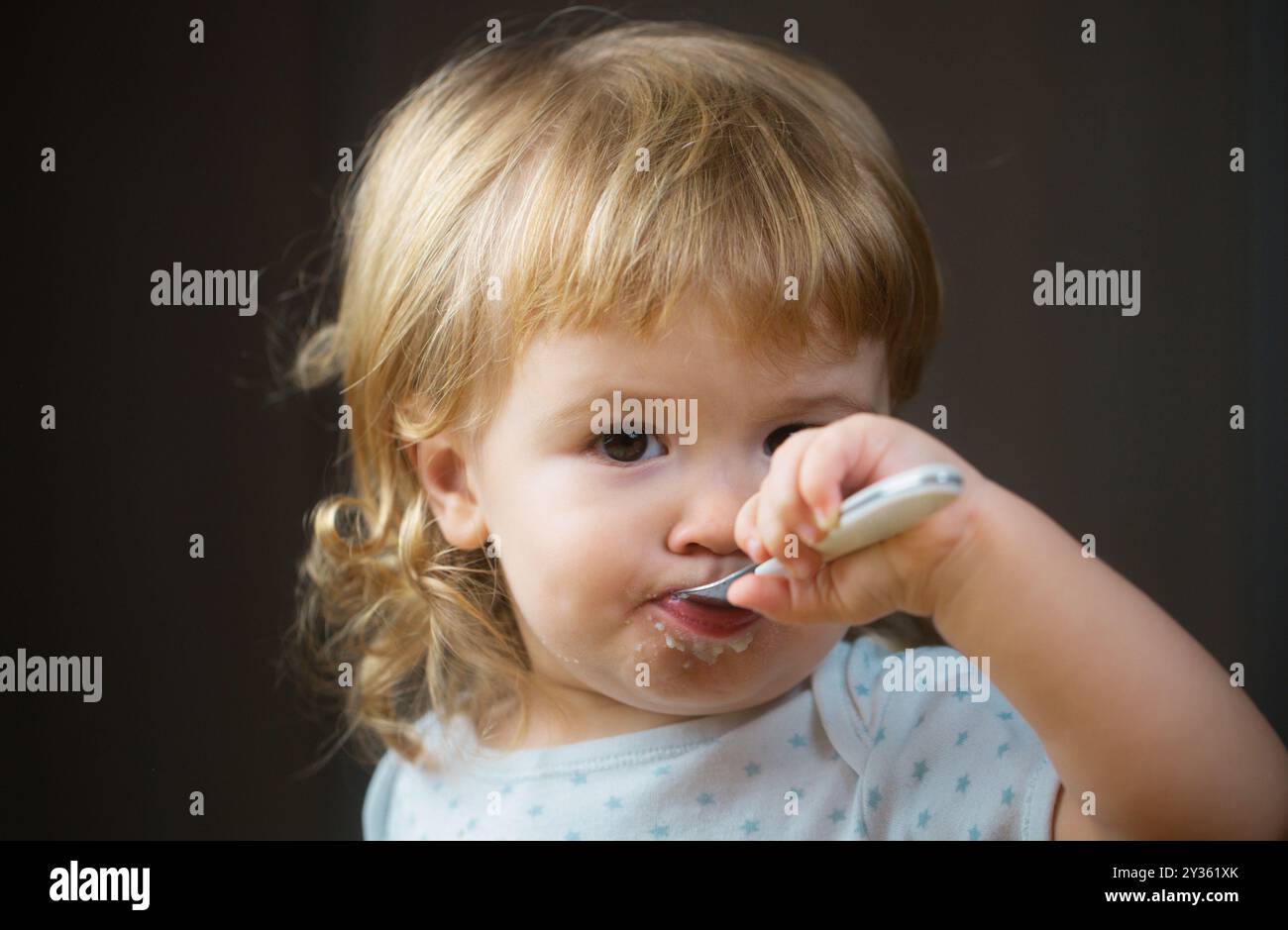 Baby eating with dirty face. Cheerful smiling child child eats itself ...