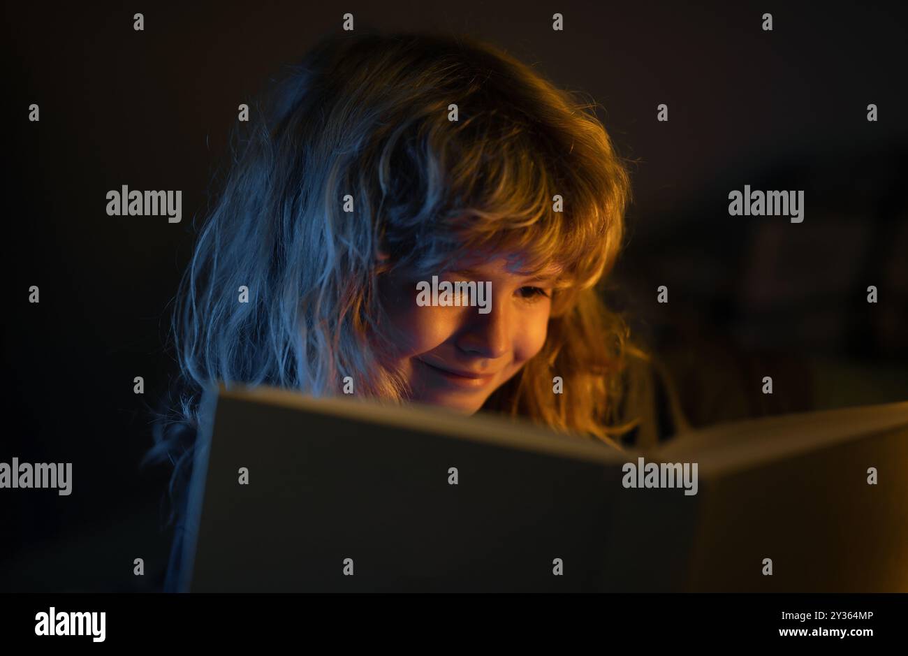 Child reading bedtime story in dark room. Kid reading a book in bed ...