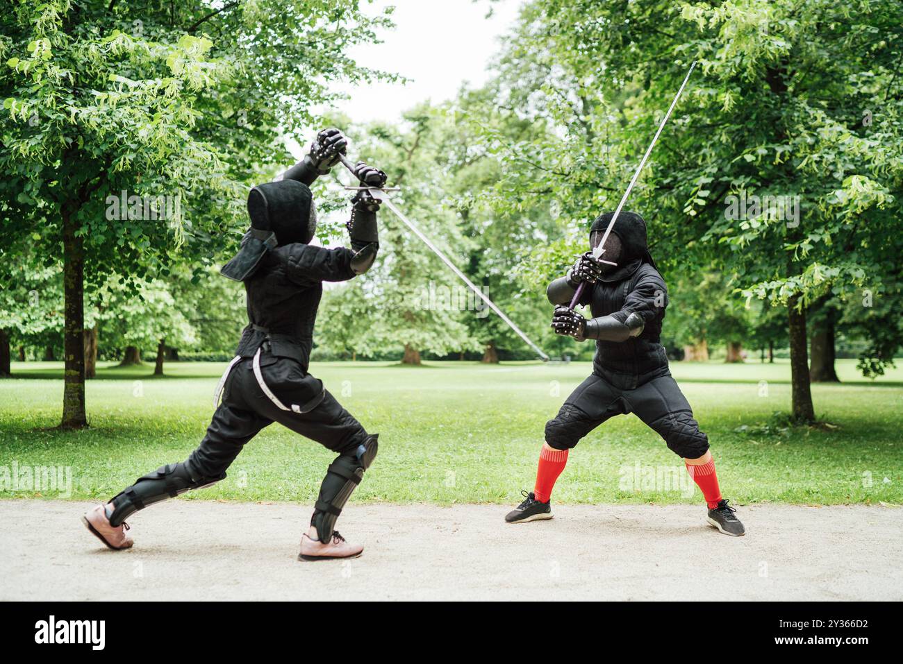 Two fencers dressed in black protective uniforms, helmets with face ...