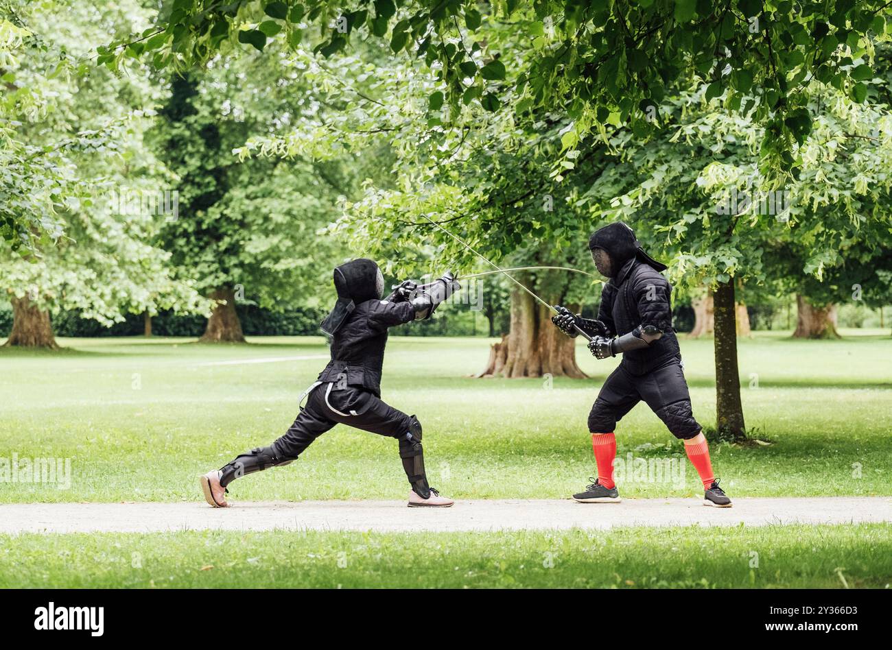 Two fencers dressed in black protective uniforms, helmets with face ...