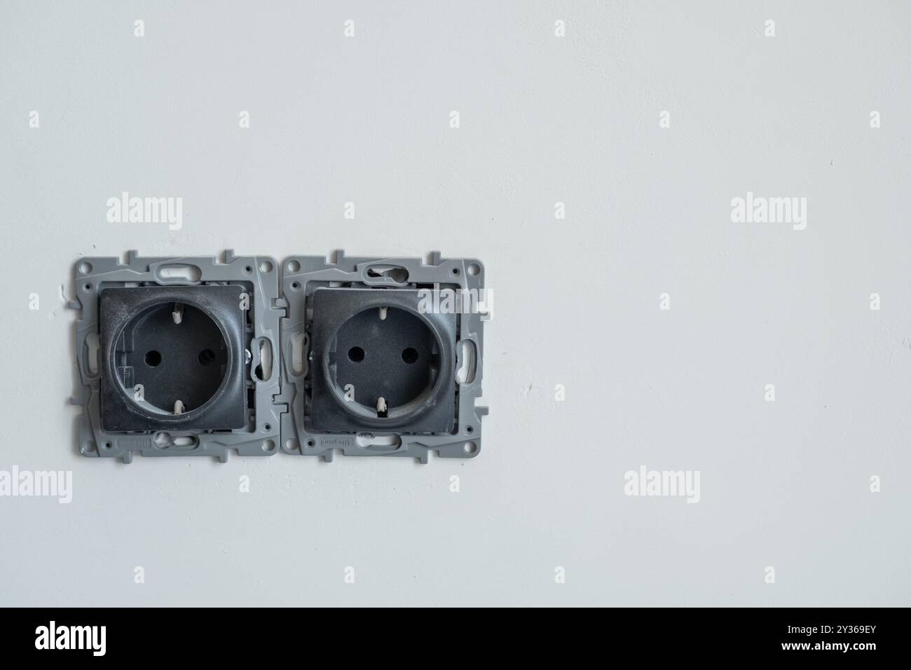 Two empty electrical outlets are installed on a plain white wall ...