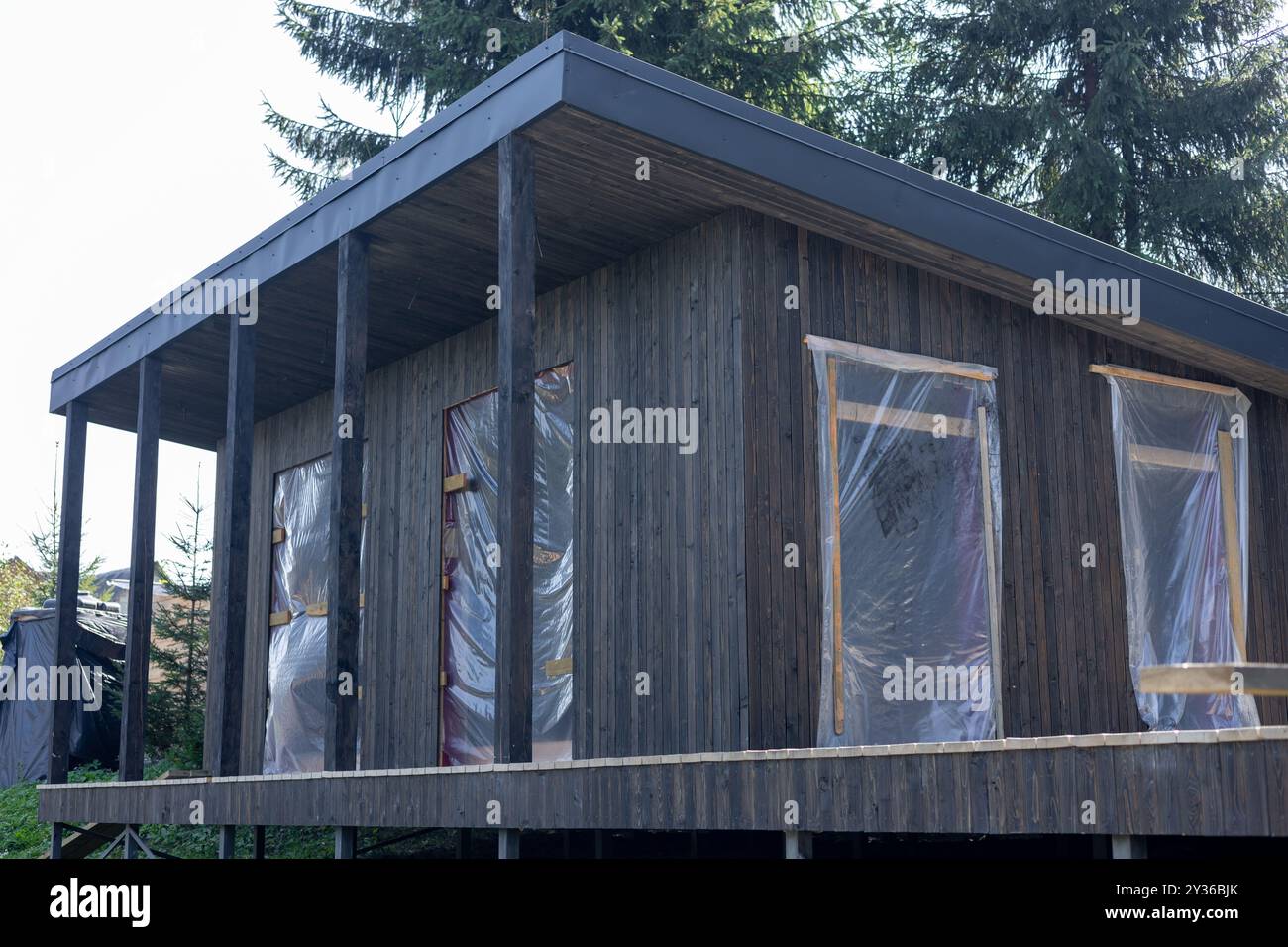 Modern cabin under construction in a wooded area during a clear day ...