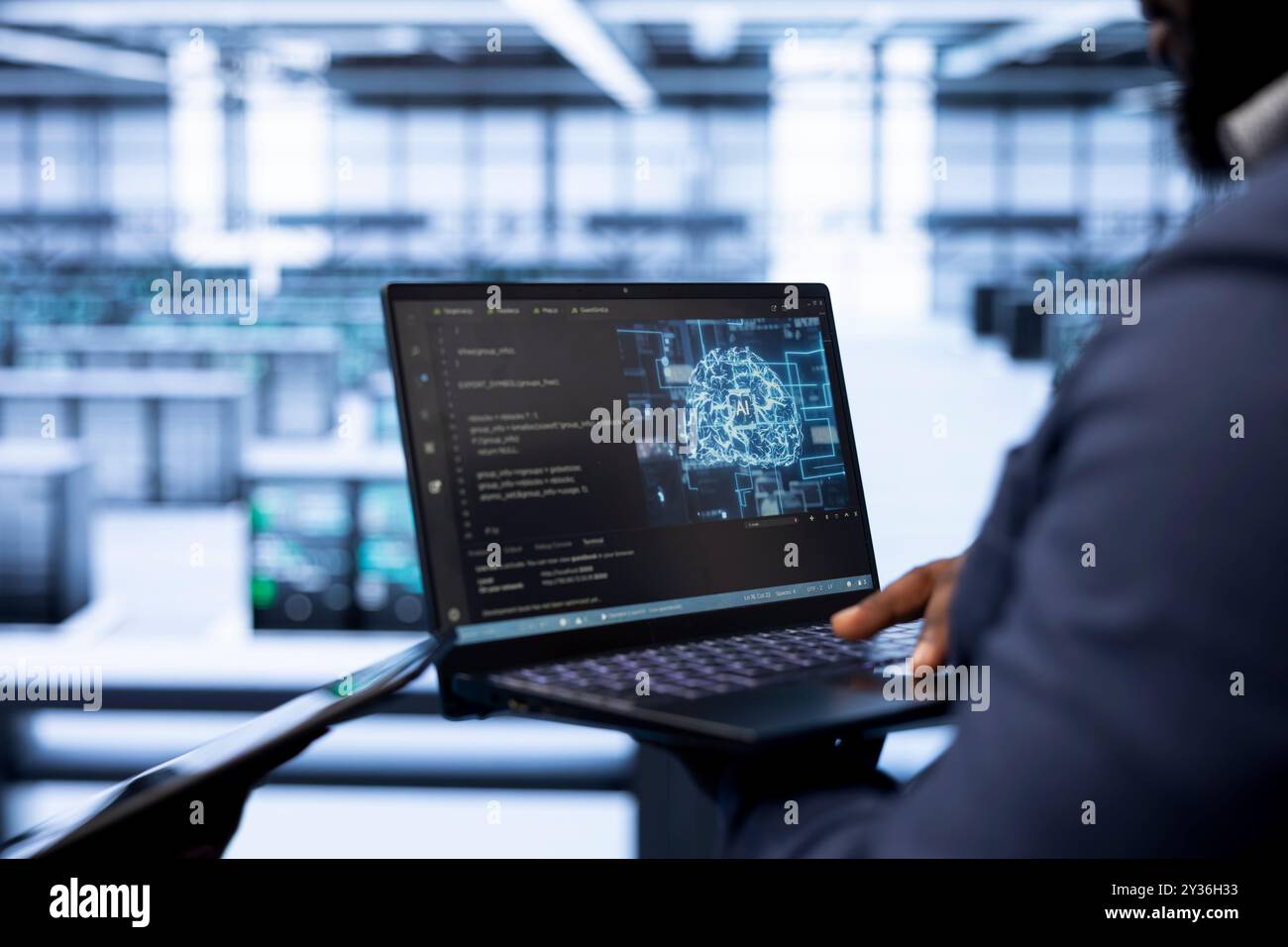 System administrator in data center using laptop to visualize artificial intelligence neural ...