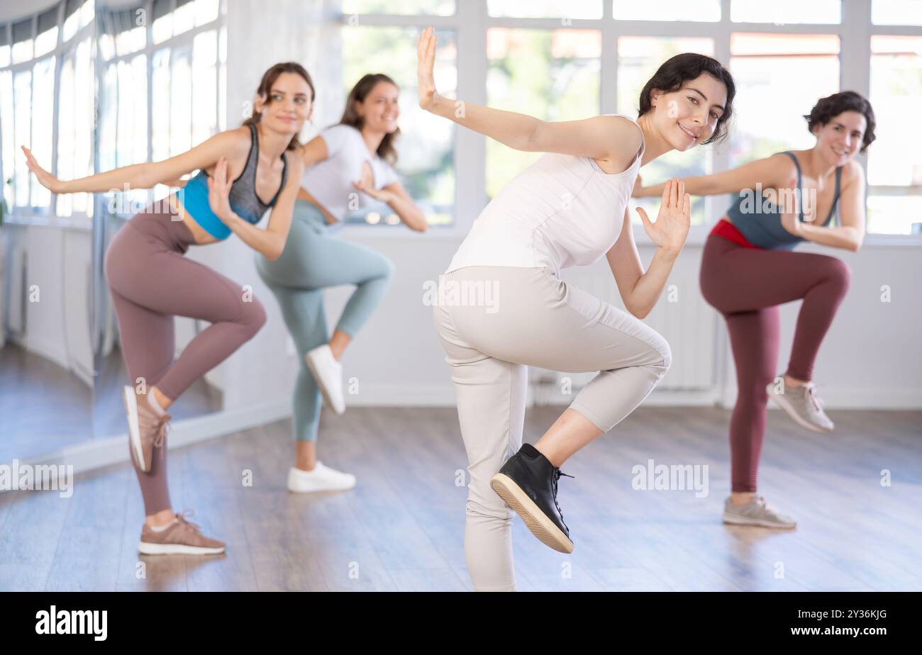 Young female teacher conducts modern dance lessons for group of girls ...