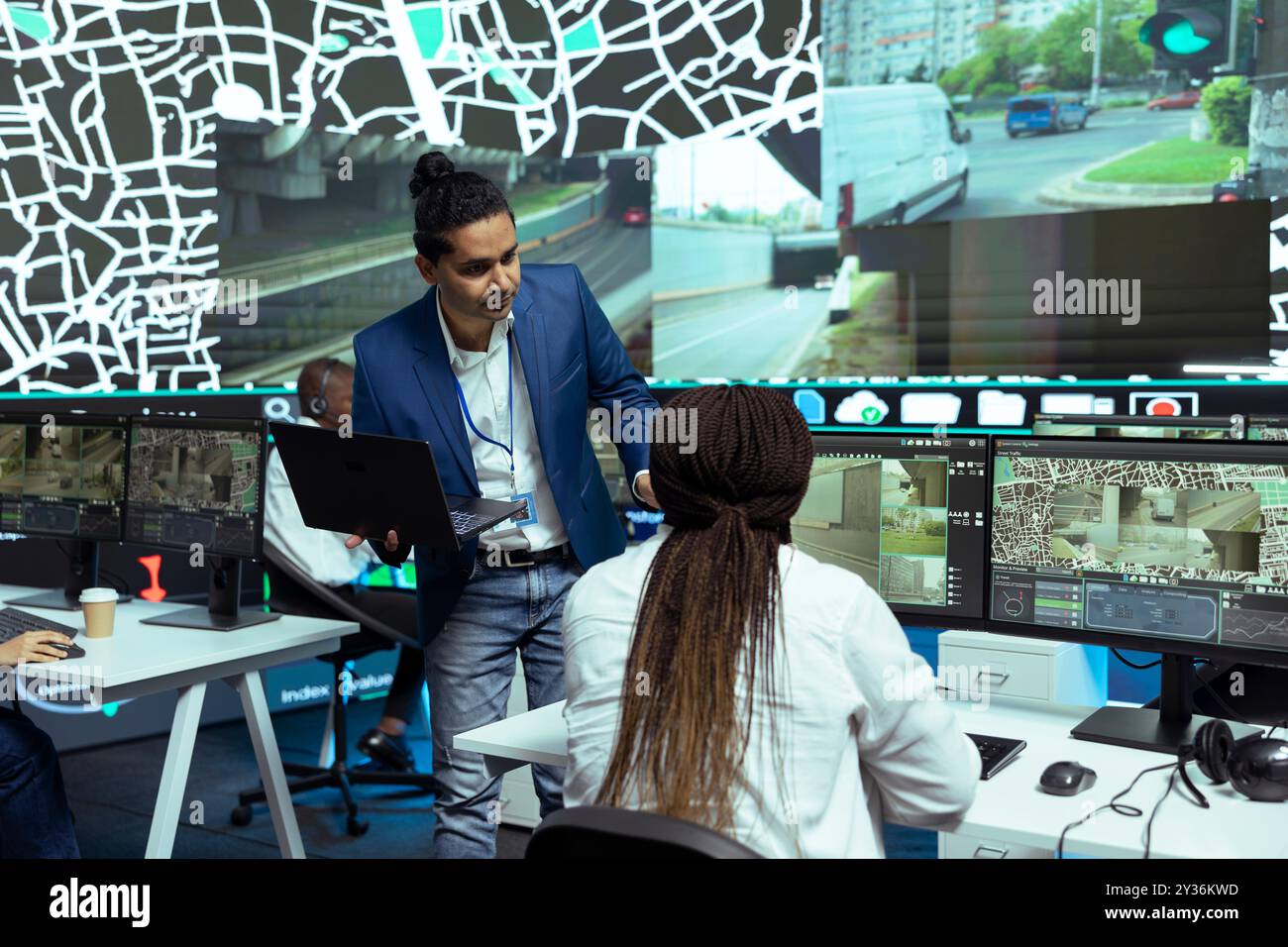 Indian man instructing his employees in using CCTV surveillance system to help couriers with ...