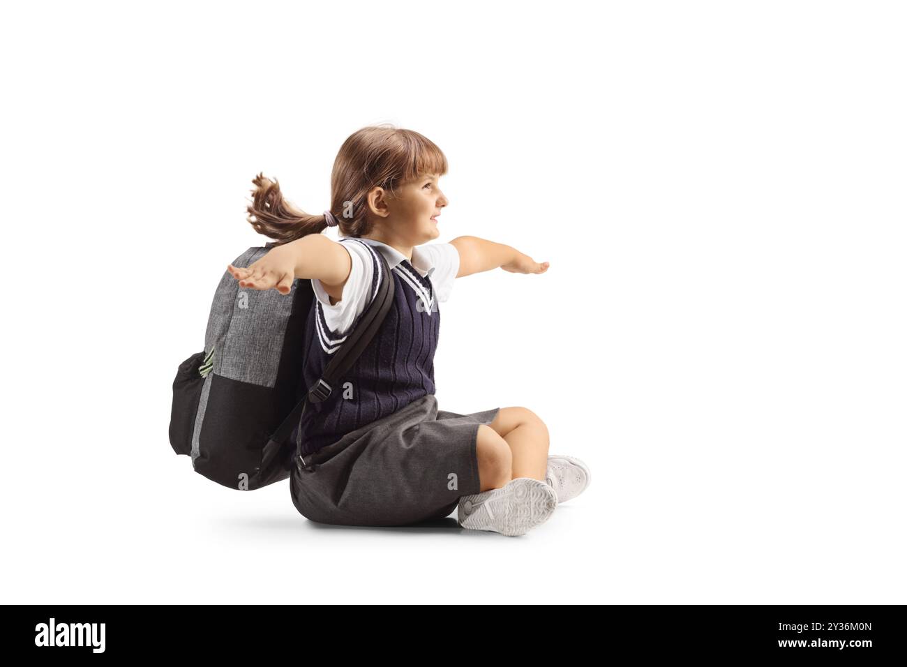 Schoolgirl in a uniform with a backpack sitting on the ground and ...