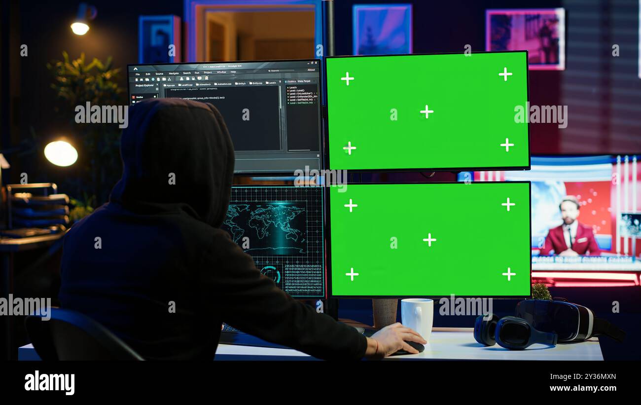 Hooded man writing lines of code on green screen PC from apartment, trying to get past security ...