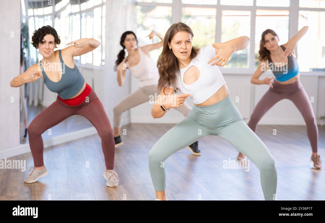 Young female teacher conducts modern dance lessons for group of girls ...