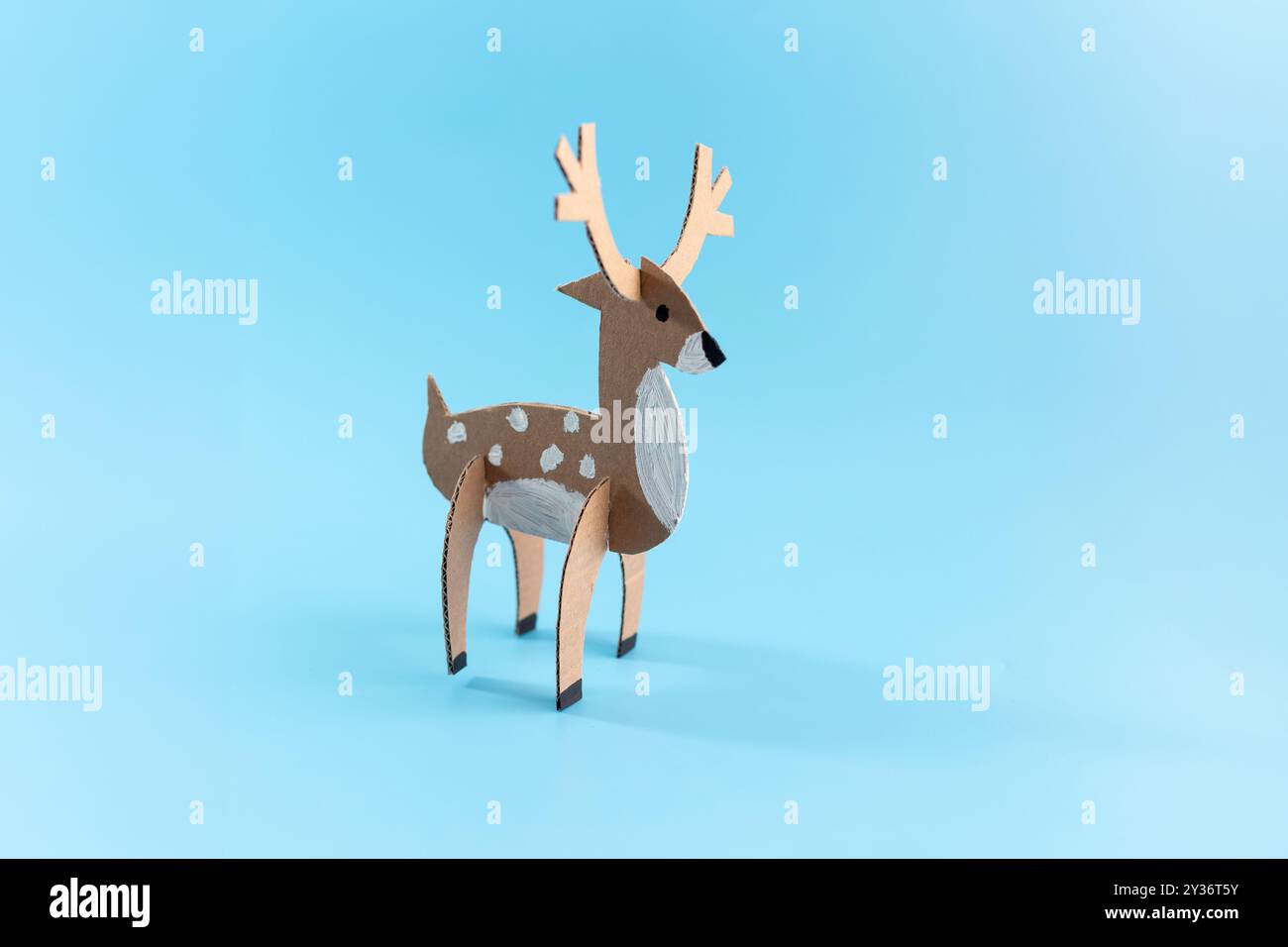 Creative paper craft model of a deer on plain background, recycling ...