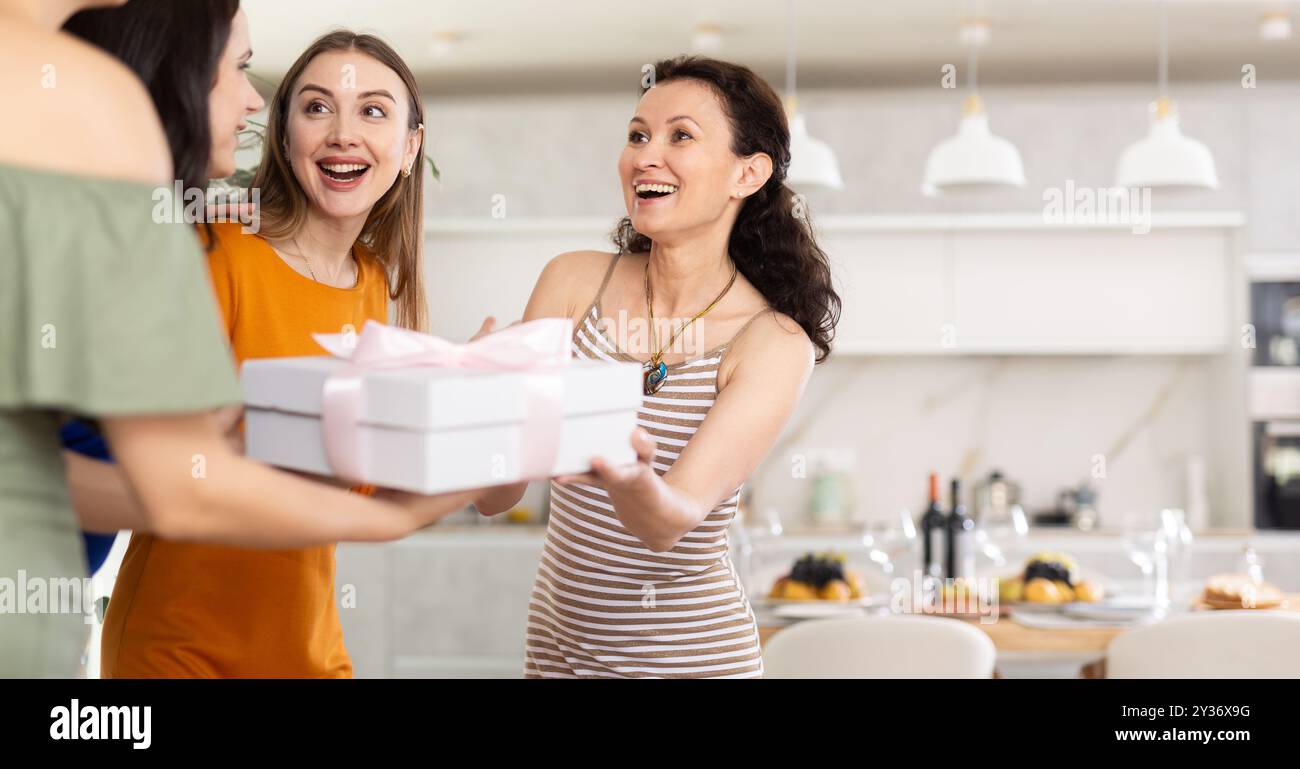 Group of women greeting each other and giving gift Stock Photo - Alamy