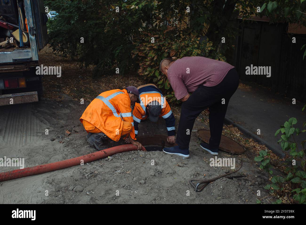 Sewer workers cleaning manhole and unblocking sewers the street ...