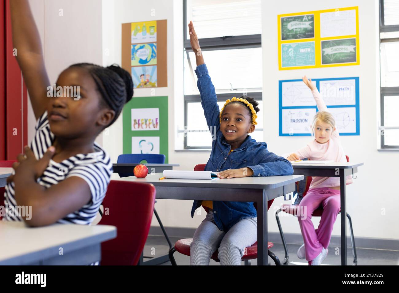 In school, multiracial girls raising hands to answer questions in ...