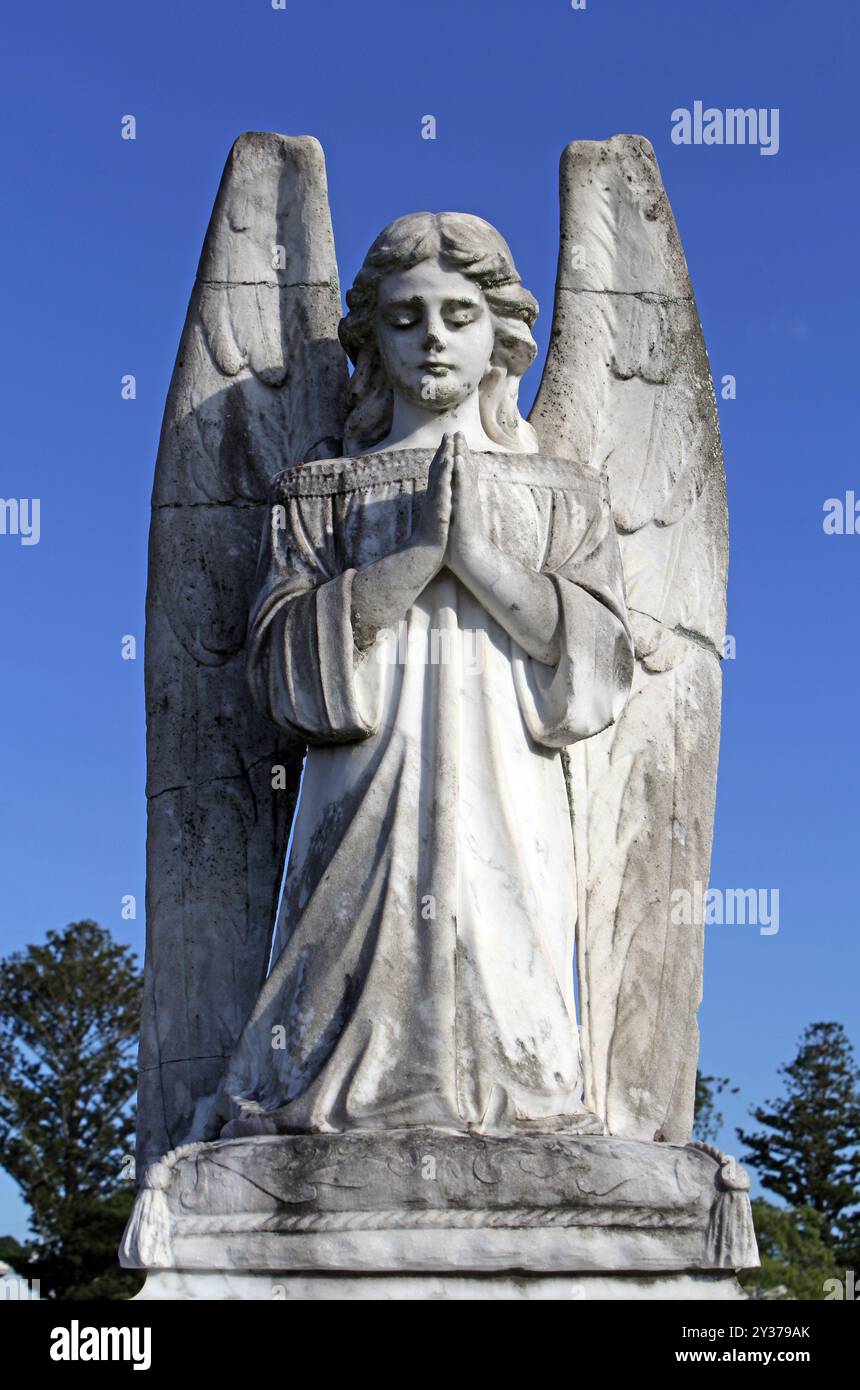 Statue of an angel praying against a blue sky background Stock Photo ...