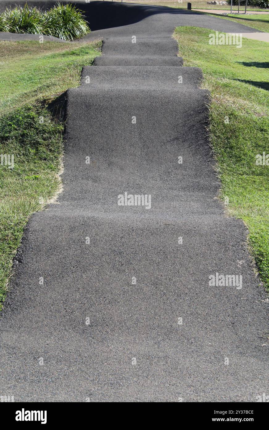 Undulating bitumen path through green grass Stock Photo - Alamy