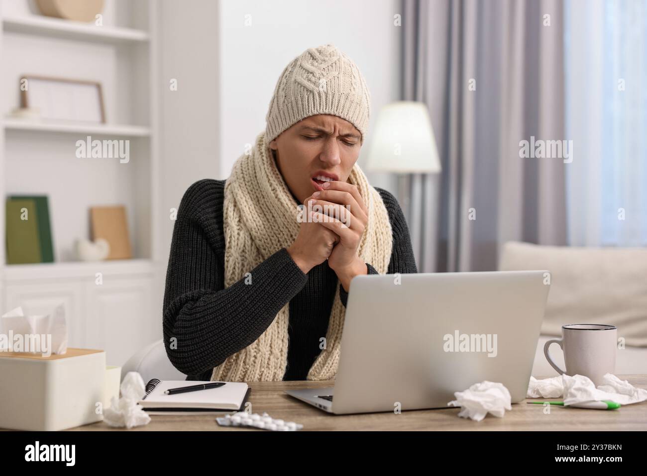 Cold symptom. Young man suffering from fever at desk indoors Stock ...