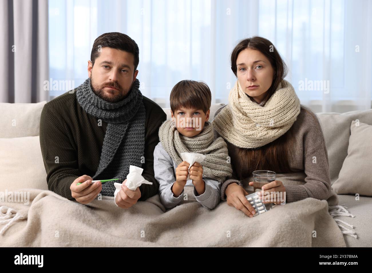 Cold symptom. Family suffering from fever on sofa at home Stock Photo ...