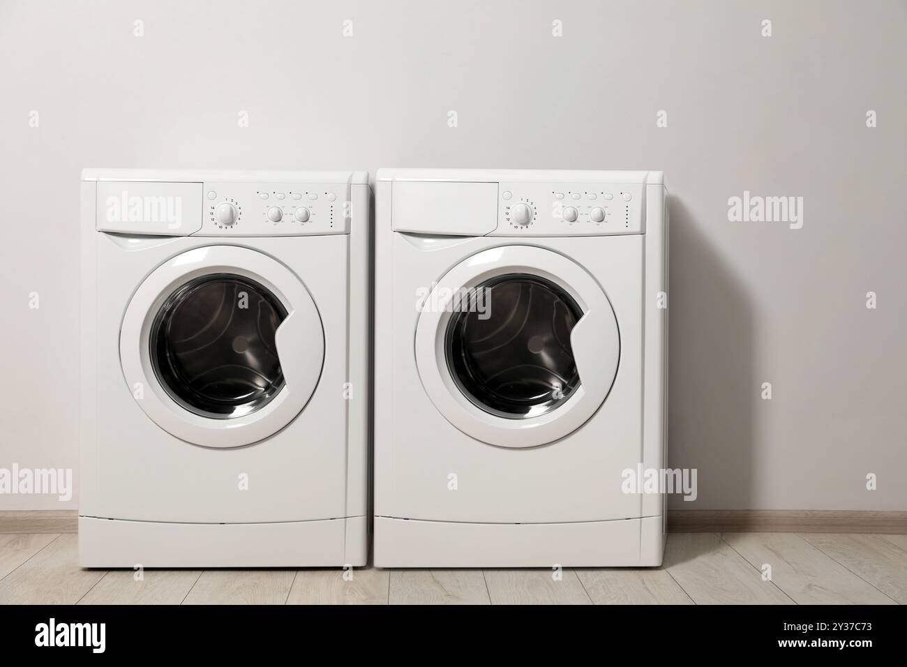 Two washing machines near light grey wall Stock Photo - Alamy