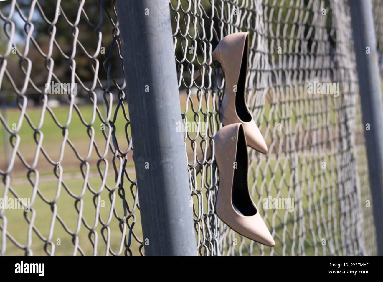 beige high heel shoes hanging from baseball field chain link fence ...