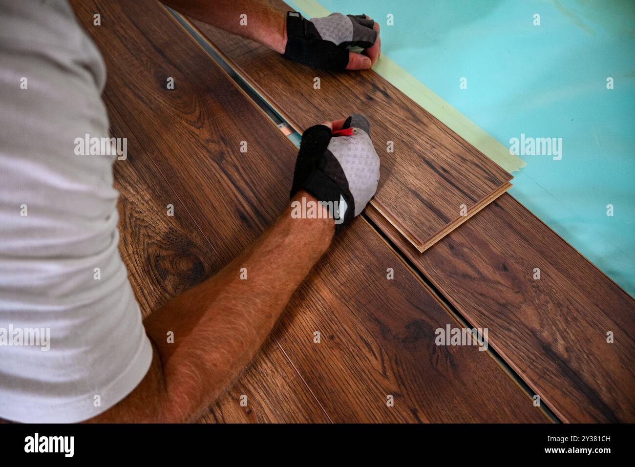 Construction worker installing new laminate wood flooring in a house ...