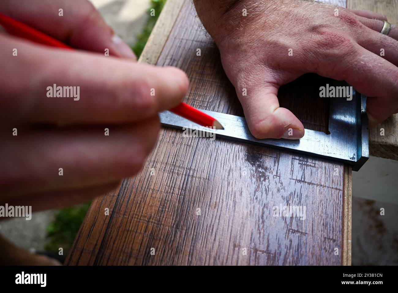 Construction worker using a carpenter square to mark a wooden plank ...