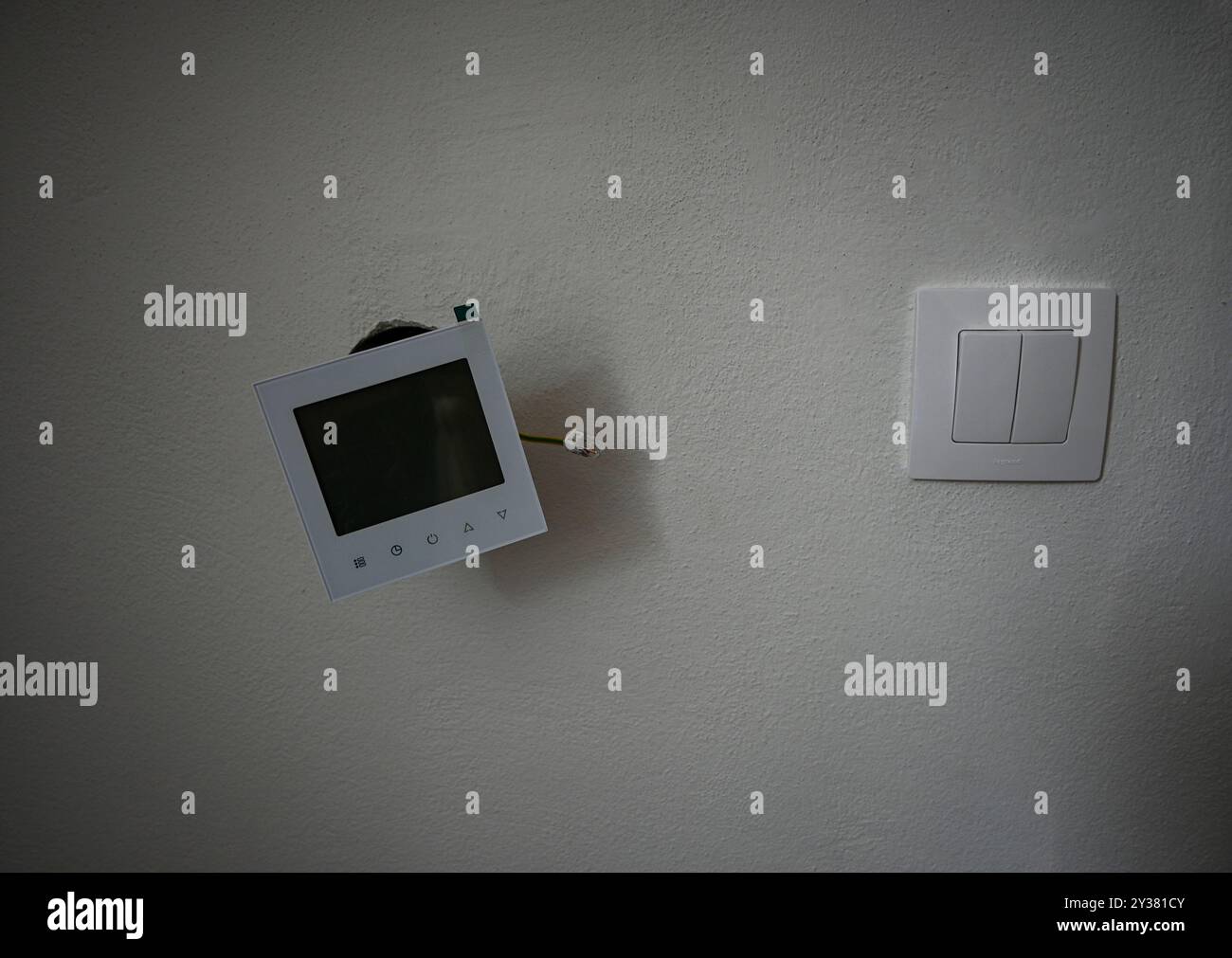 Smart home device being installed on a white wall with wires connecting ...