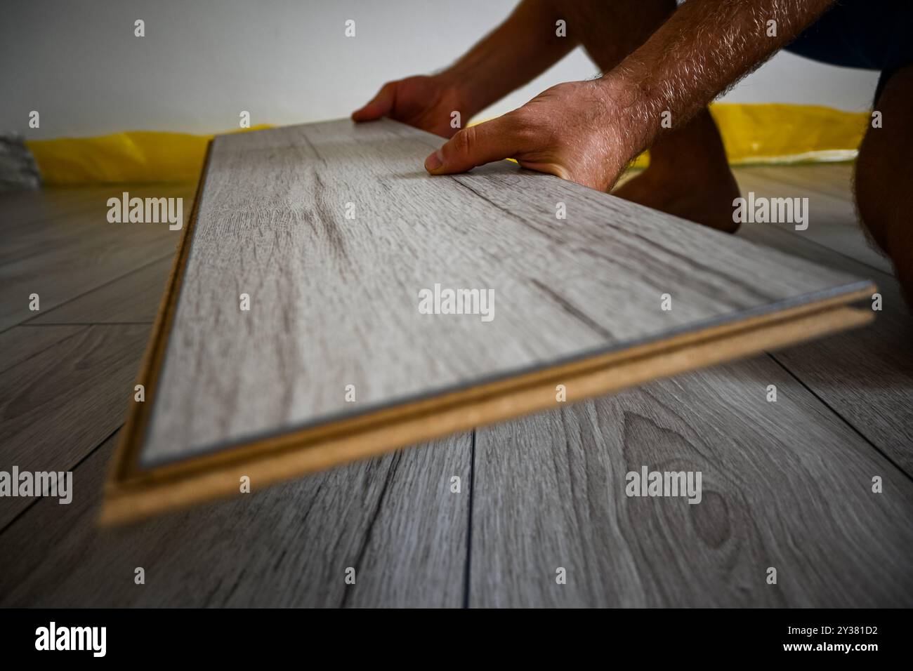 Construction worker carefully placing a new laminate floor plank during ...