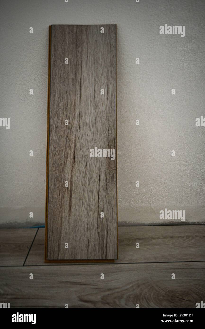Single plank of laminate flooring leaning against a white wall Stock ...