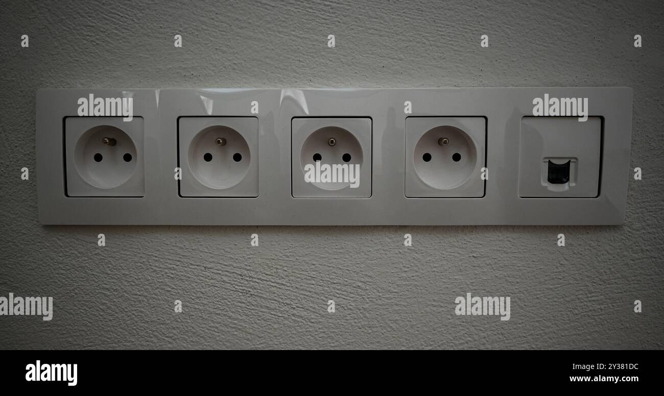 Four power sockets and internet connection are embedded in a white wall ...