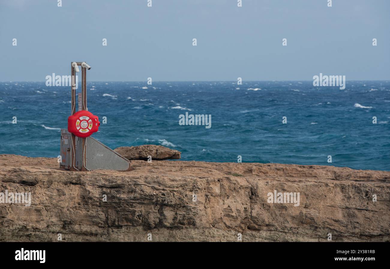 Red lifebuoy hanging on metal pole overlooking rough sea Stock Photo ...