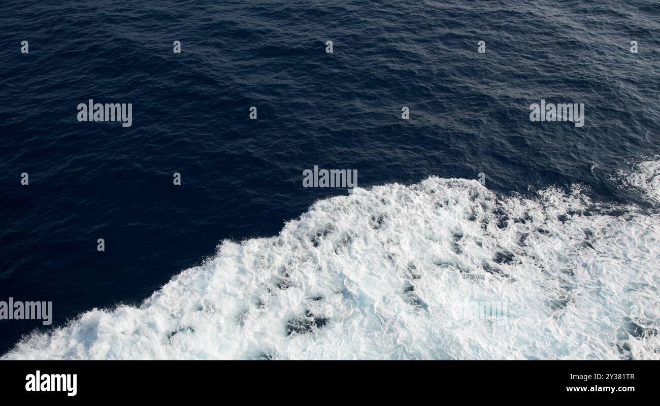 Deep blue ocean water meeting white wash of boat wake Stock Photo - Alamy
