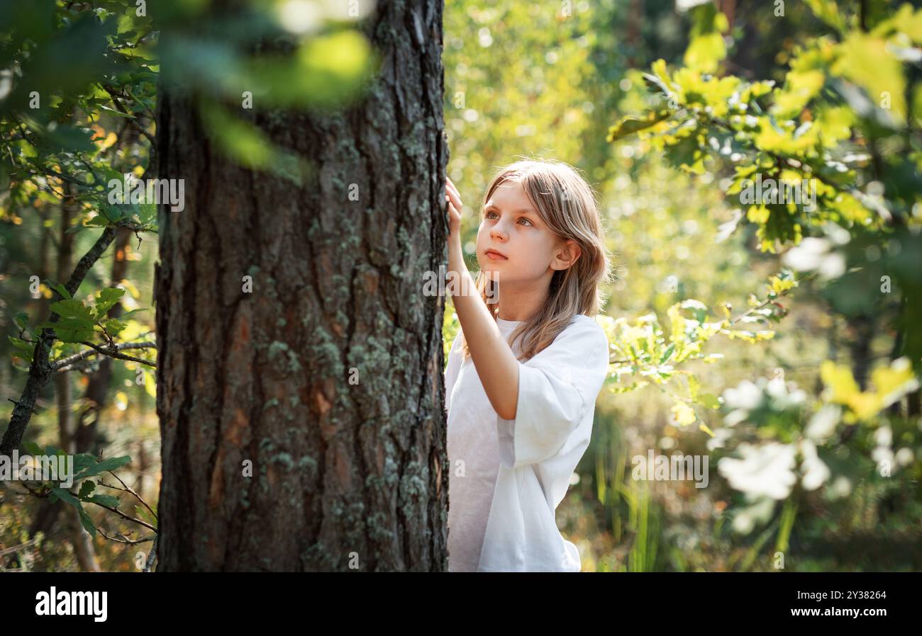 A teenage girl hugs a tree in the forest. Hugging and touching trees to ...