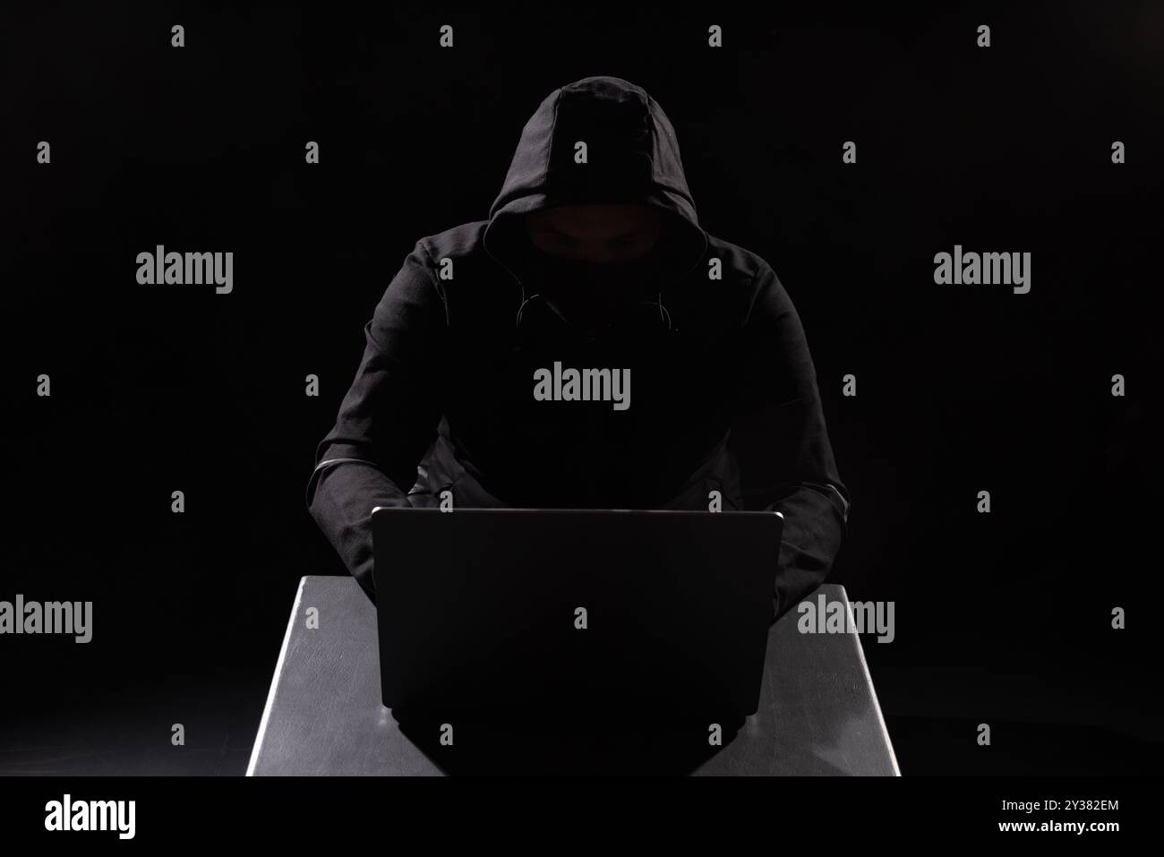 Cyber hacker in hood behind laptop in dark room, digital cyber security ...
