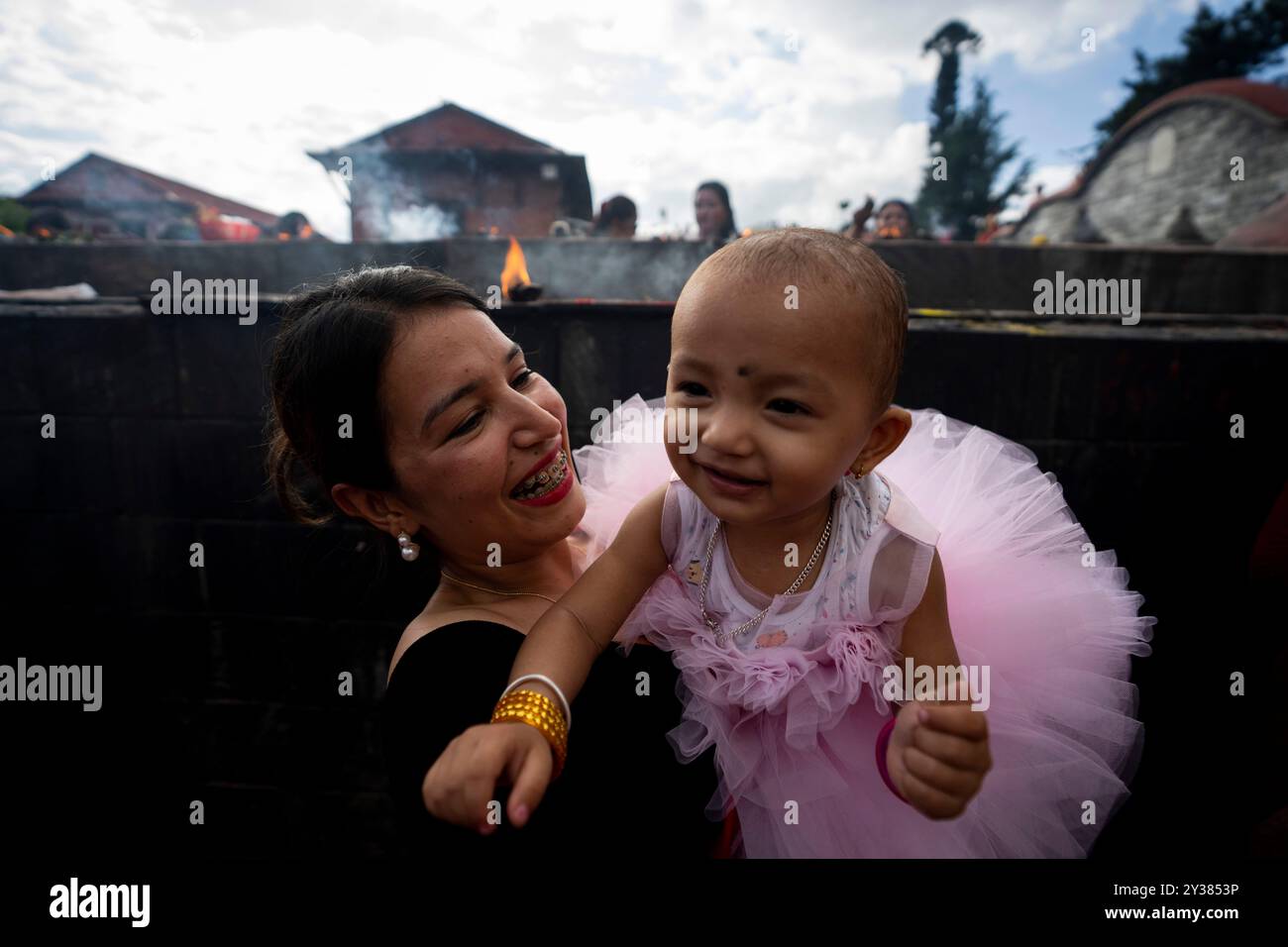 A woman plays with her child at the Pashupatinath temple during Teej festival celebrations in ...