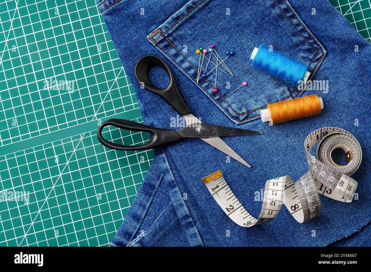 Sewing tools on a cutting mat with denim and thread spools in a craft ...