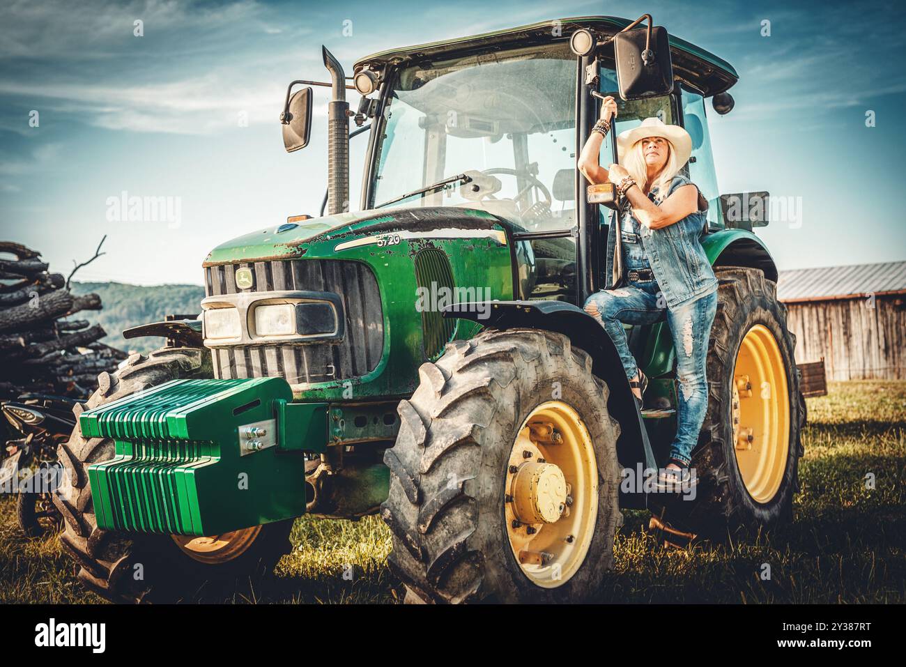 A woman in a cowboy hat poses on a tractor Stock Photo - Alamy