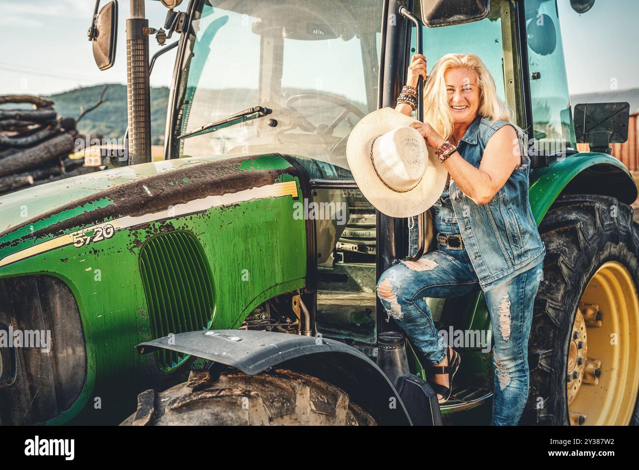 A woman in a cowboy hat poses on a tractor Stock Photo - Alamy