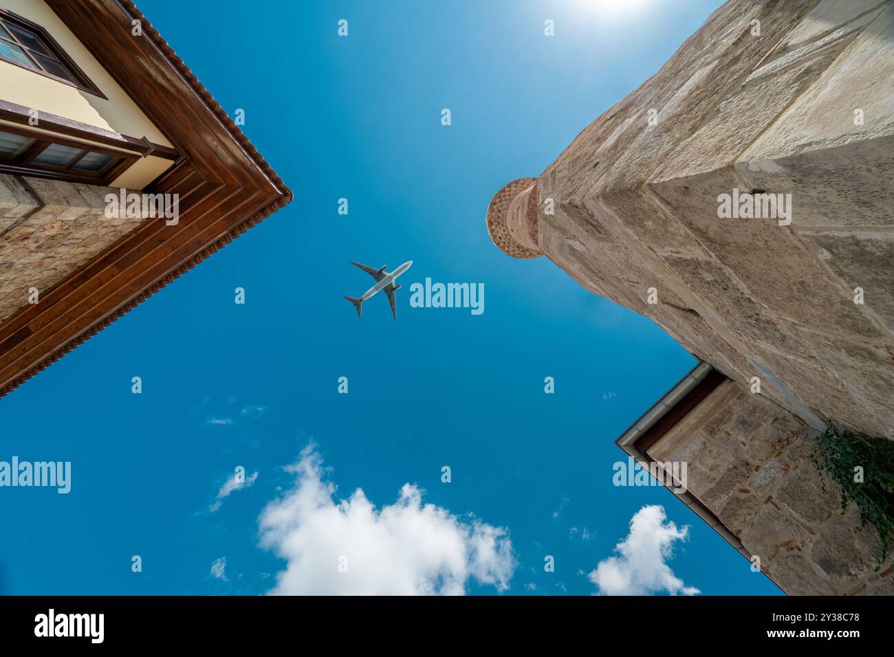 Passenger plane flying over the historical house and truncated minaret ...