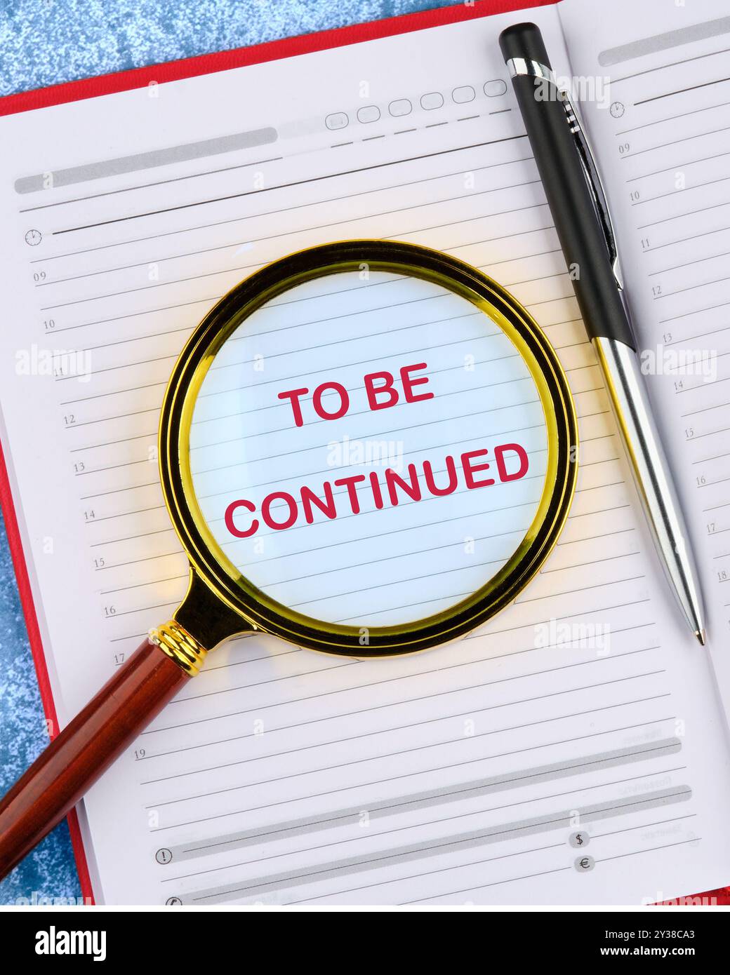 TO BE CONTINUED text written in an open notebook through a magnifying ...