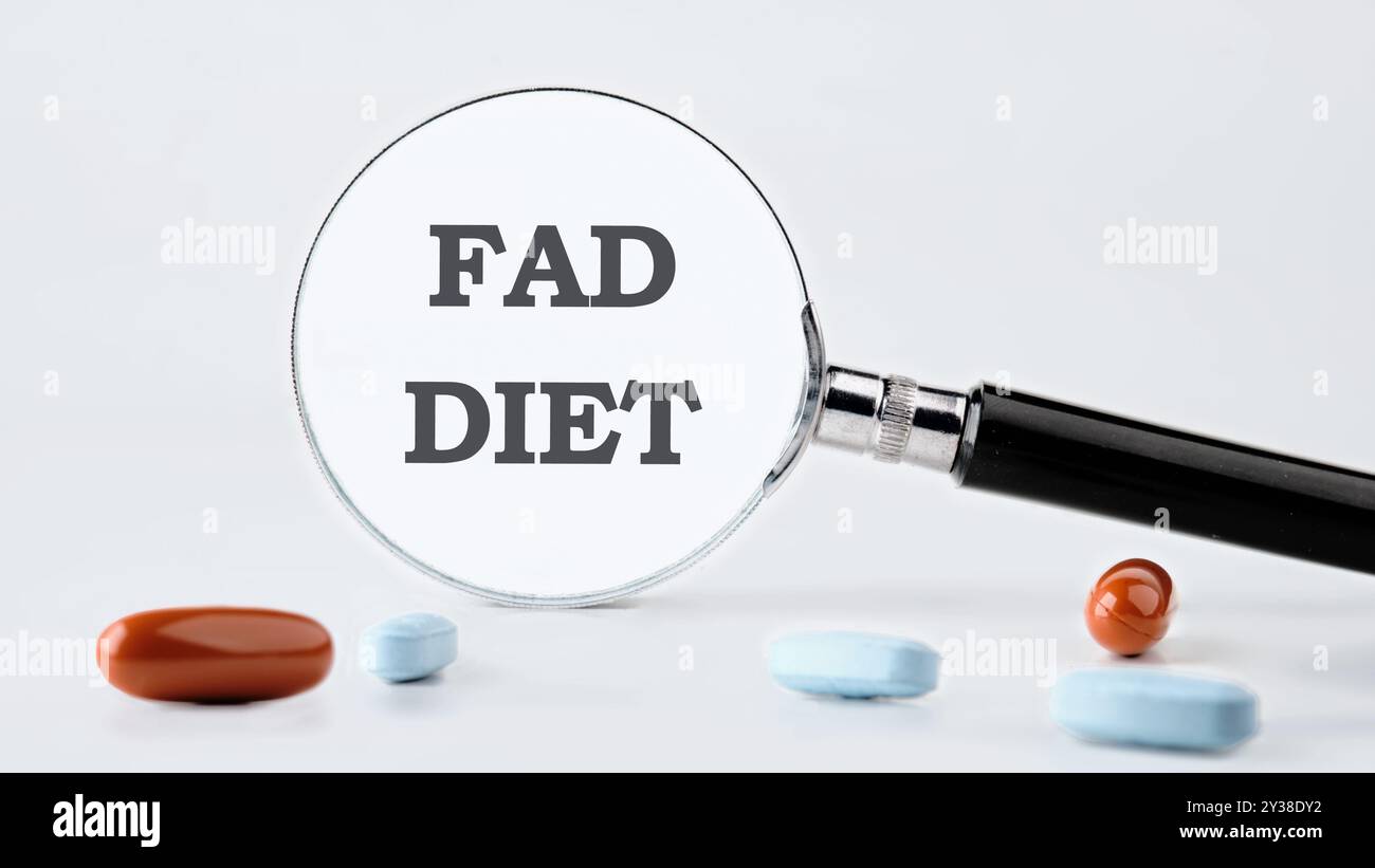 The phrase FAD DIET through a magnifying glass on a white background of ...