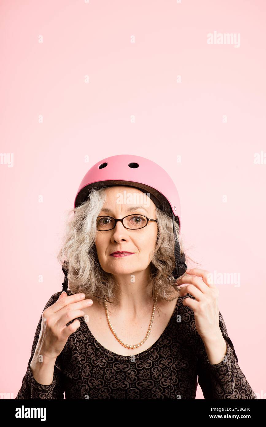Glasses, helmet and portrait of old woman in studio isolated on pink ...