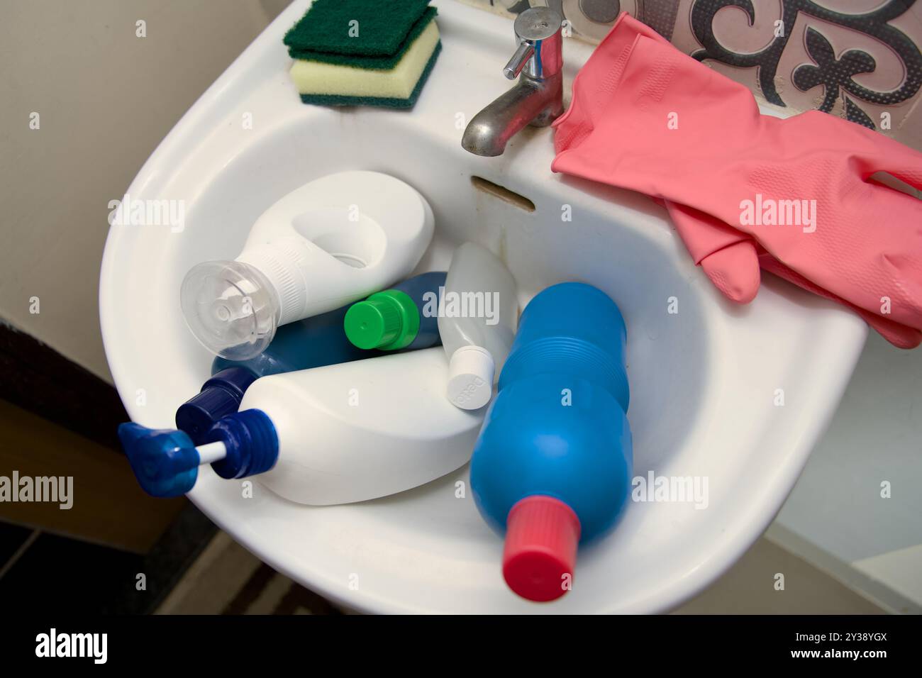 Bathroom sink overflowing with brightly colored cleaning products and ...